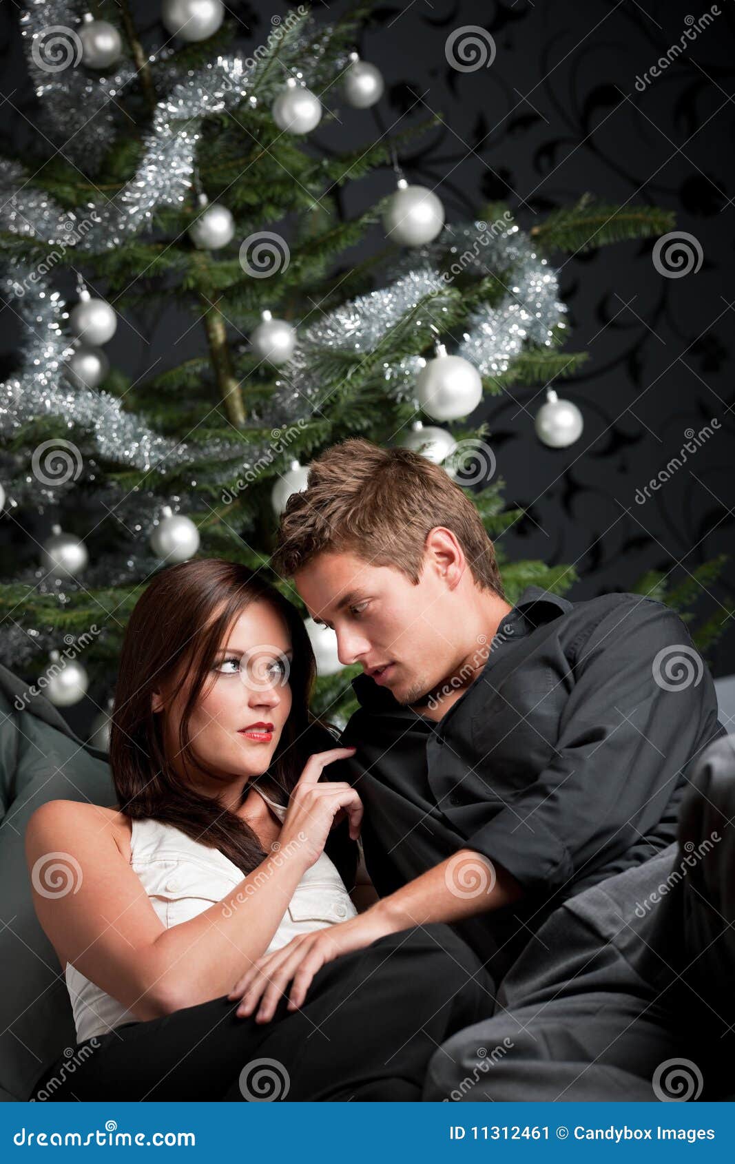 Young Couple in Front of Christmas Tree Stock Image - Image of sitting ...