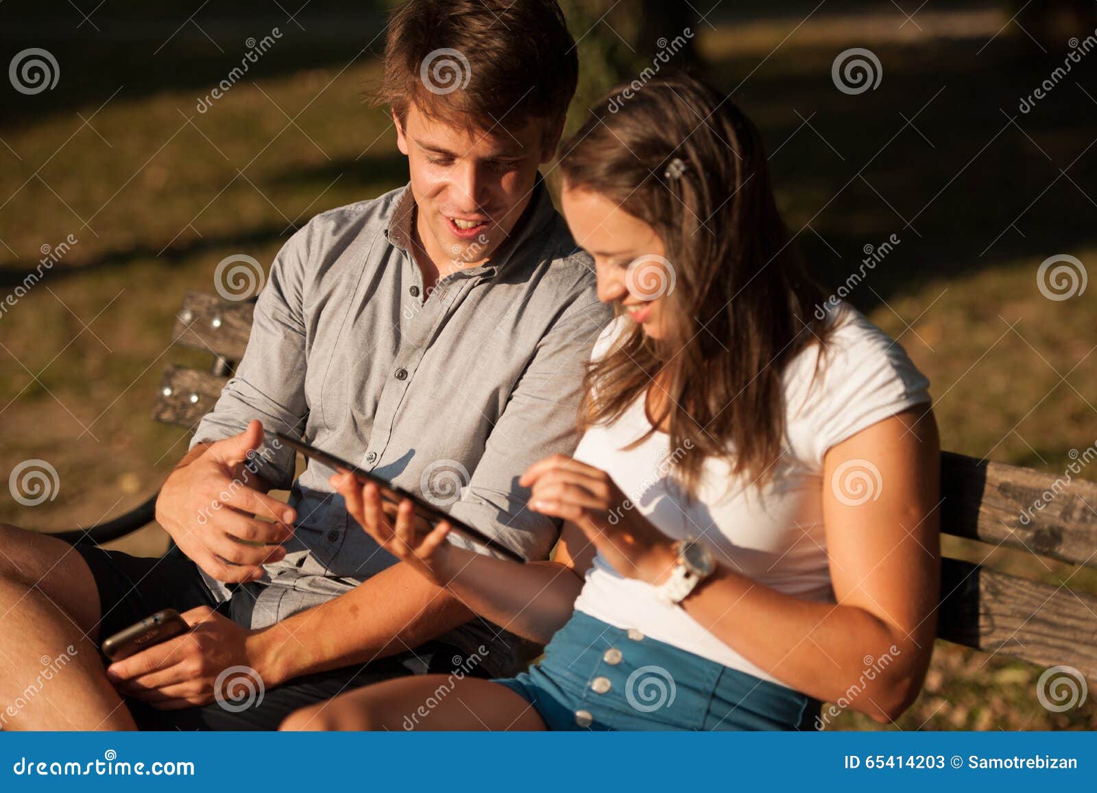 Young Couple Having Fun on a Bench in Park while Socializing Over Web ...