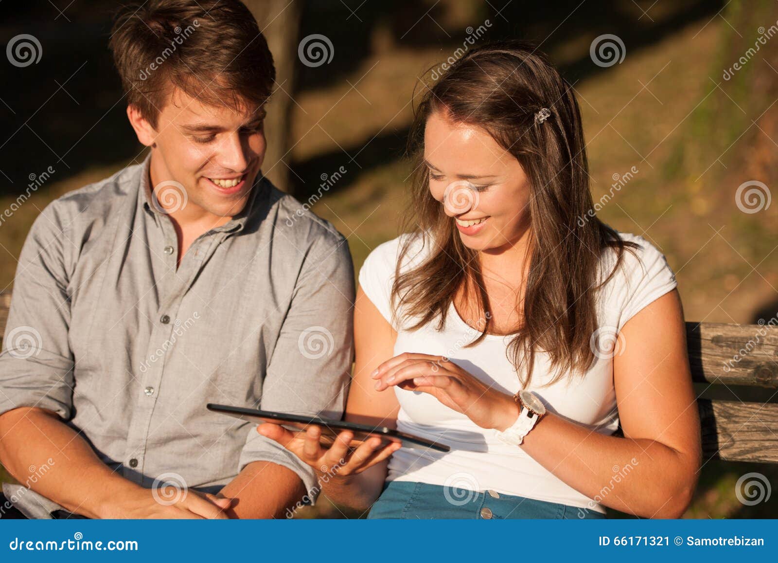 Young Couple Having Fun on a Bench in Park while Socializing Over Web ...