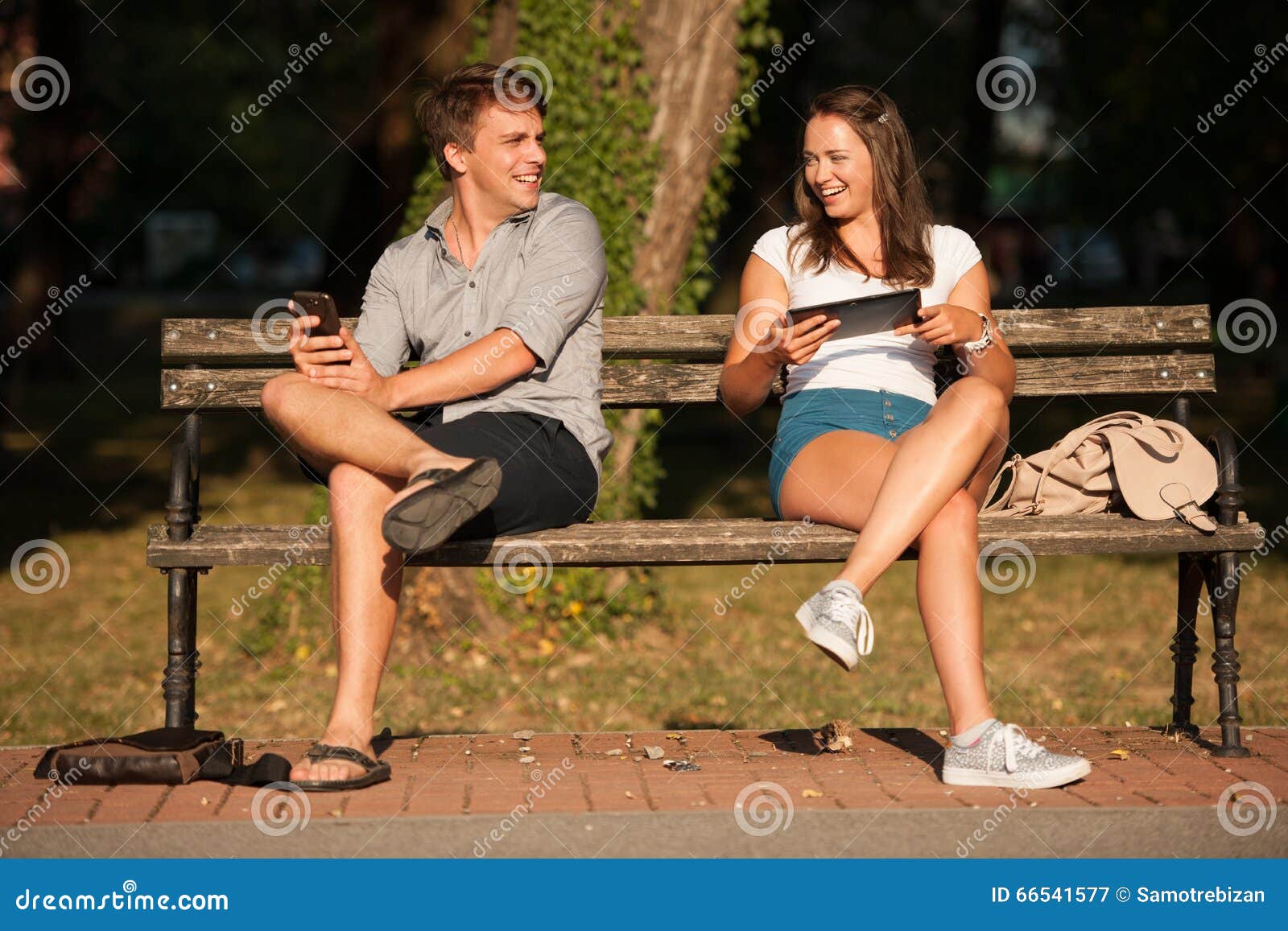 Young Couple Having Fun on a Bench in Park while Socializing Over Web ...