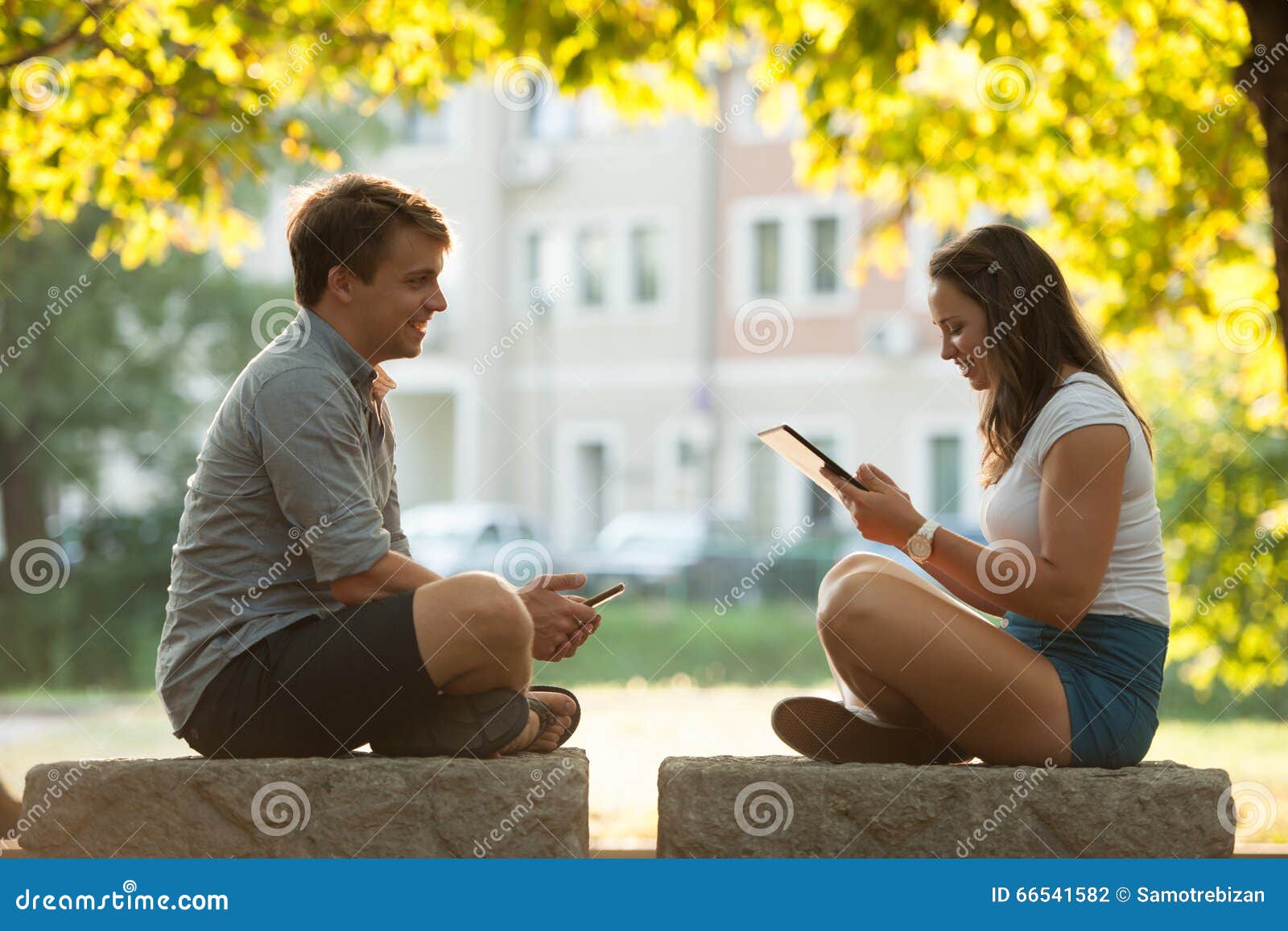 Young Couple Having Fun on a Bench in Park while Socializing Over Web ...