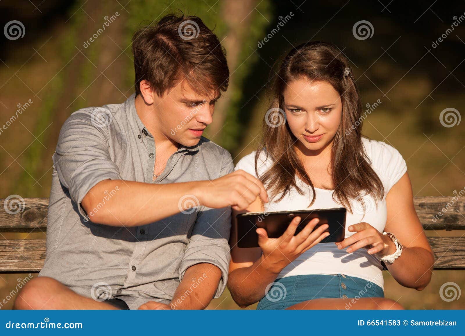 Young Couple Having Fun on a Bench in Park while Socializing Over Web ...