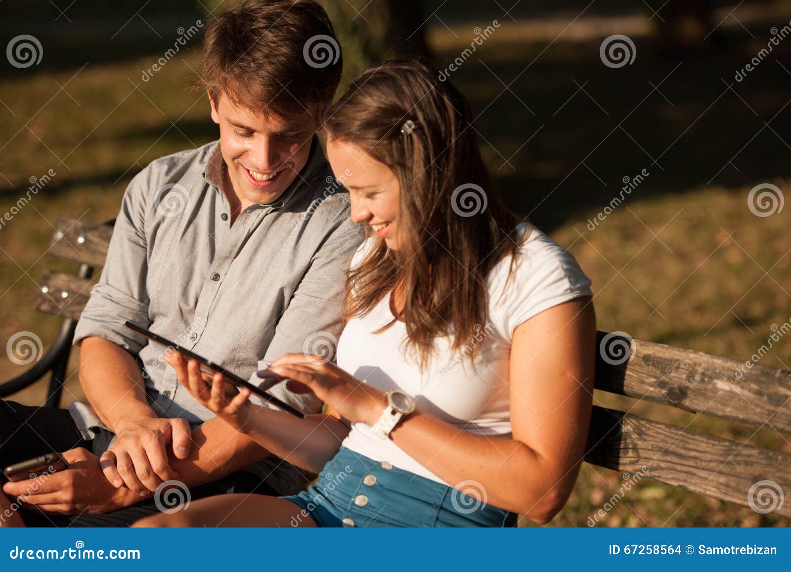 Young Couple Having Fun on a Bench in Park while Socializing Over Web ...