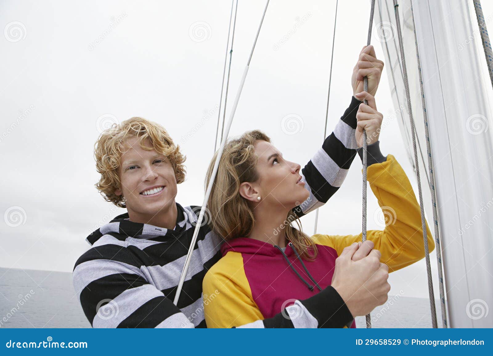 Young Couple Holding Rigging on Sailboat Stock Image - Image of ...