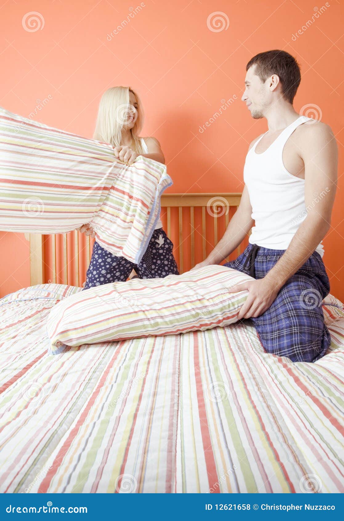 Young Couple Kneeling on Bed Having a Pillow Fight Stock Photo - Image ...