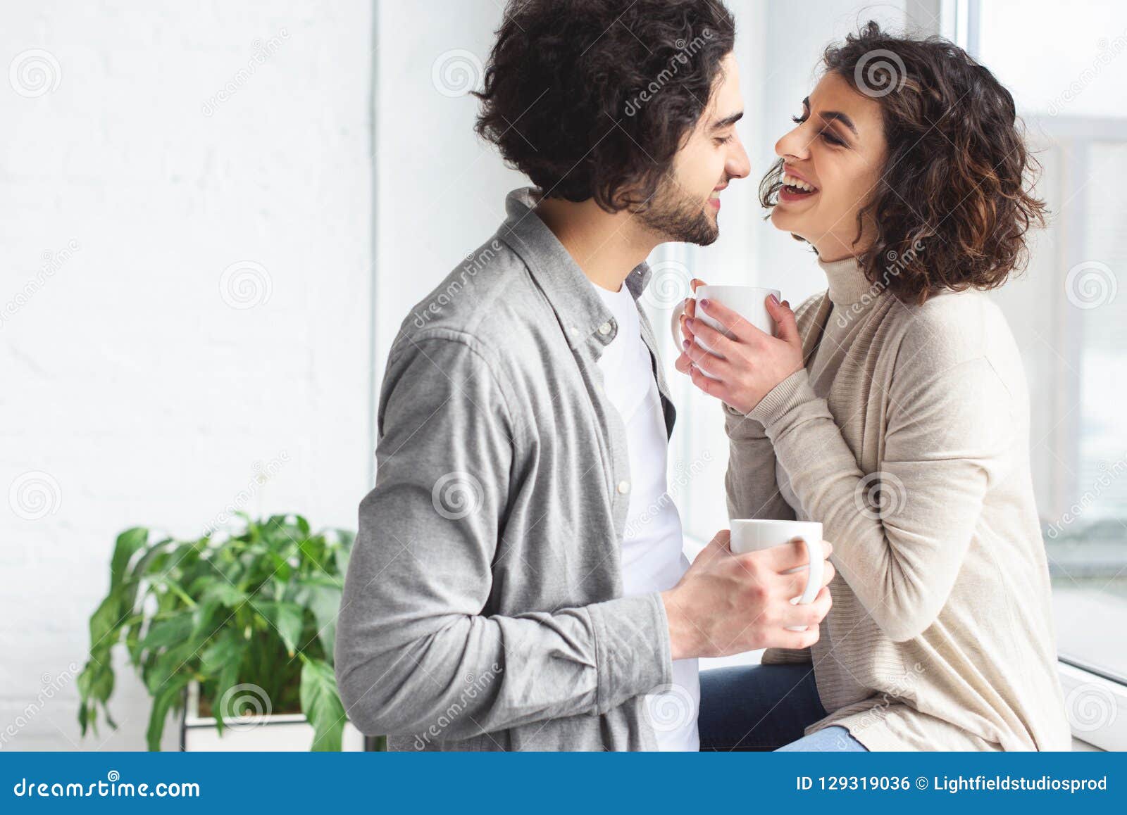 Young Couple Laughing and Holding Cups of Tea Stock Photo - Image of ...