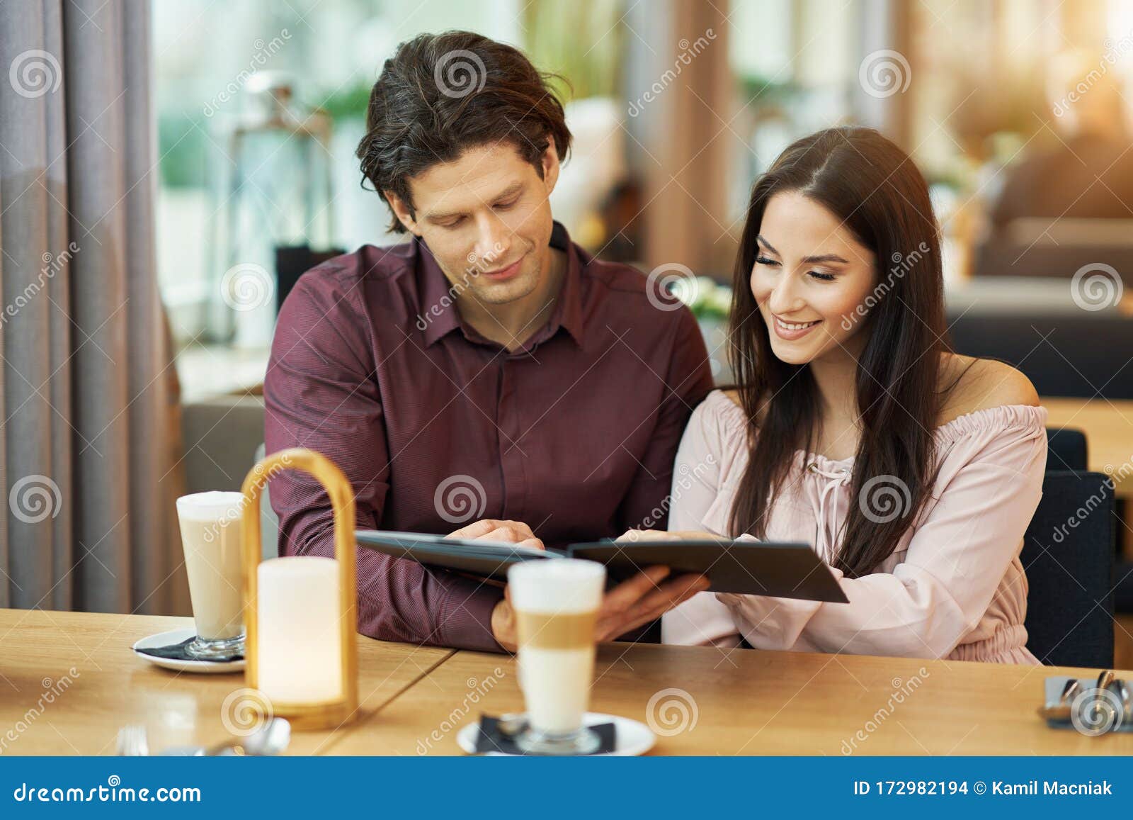 Young Couple Looking at Menu in Cafe Stock Photo - Image of male ...