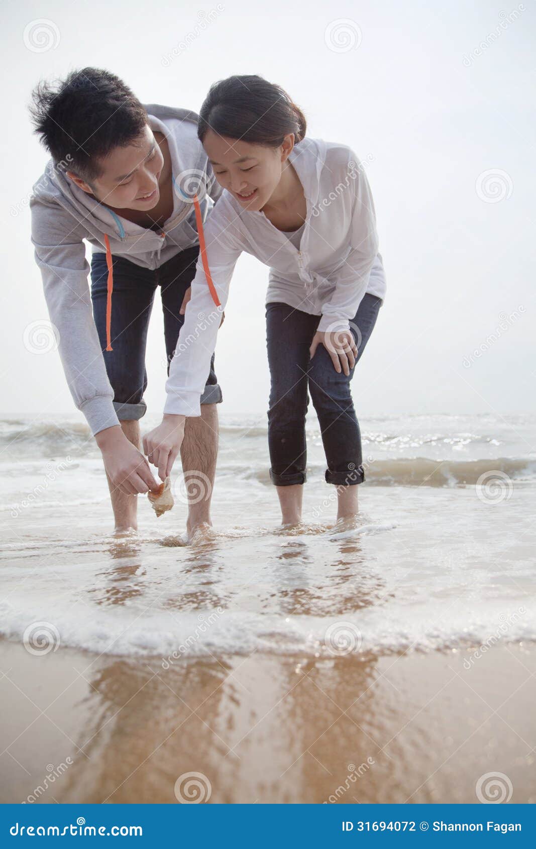 Young Couple Looking at Seashells on the Beach Stock Photo - Image of ...