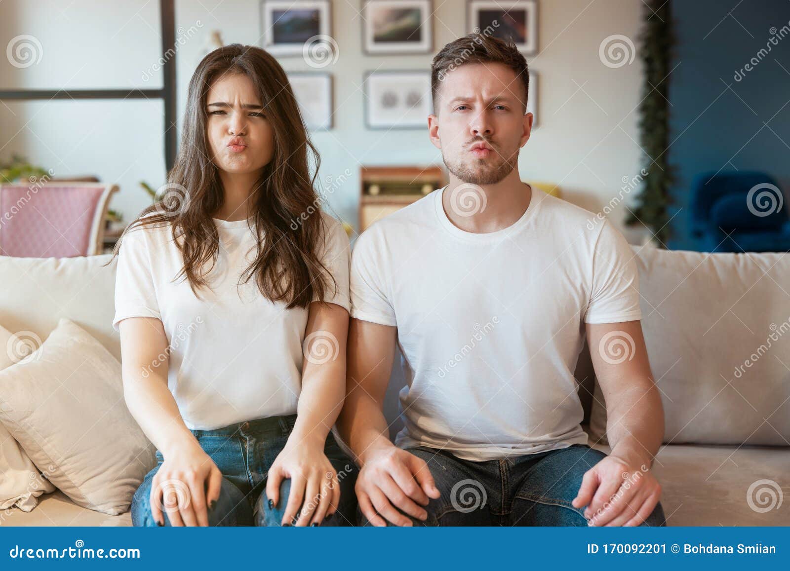 Young Couple Man And Woman Sitting On The Sofa Looking Upset Grimacing