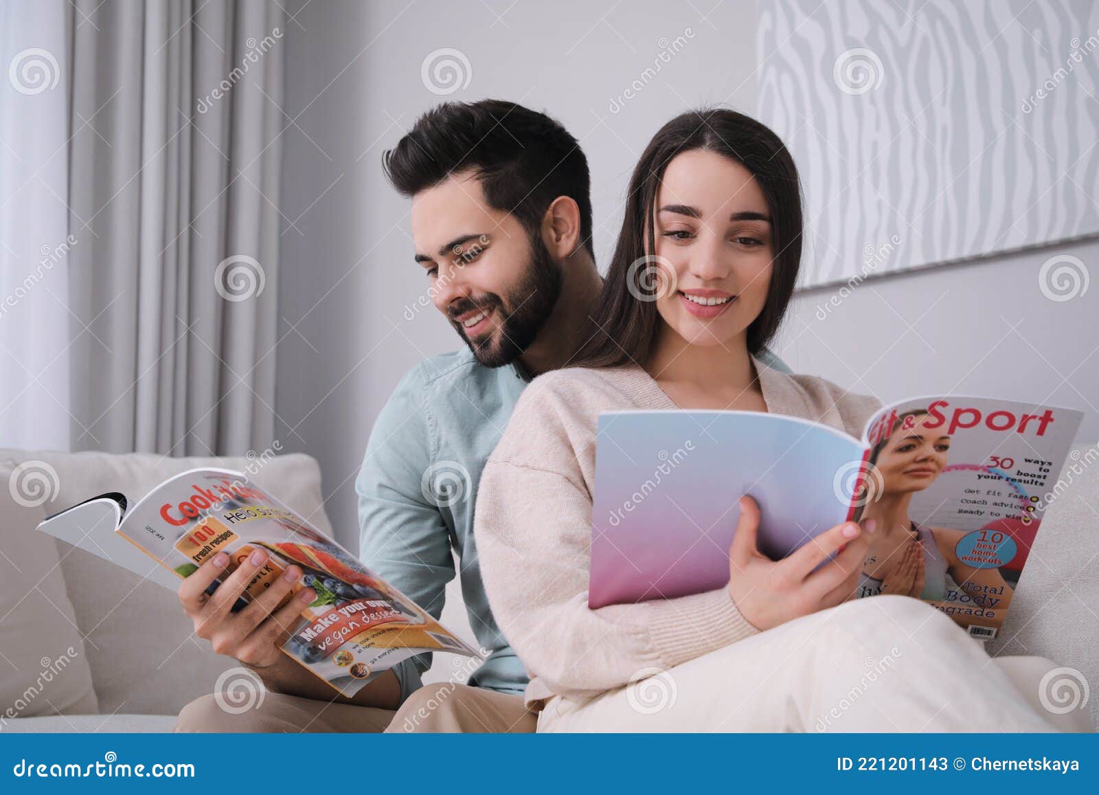 Young Couple Reading Magazines on Sofa at Home Stock Image - Image of ...