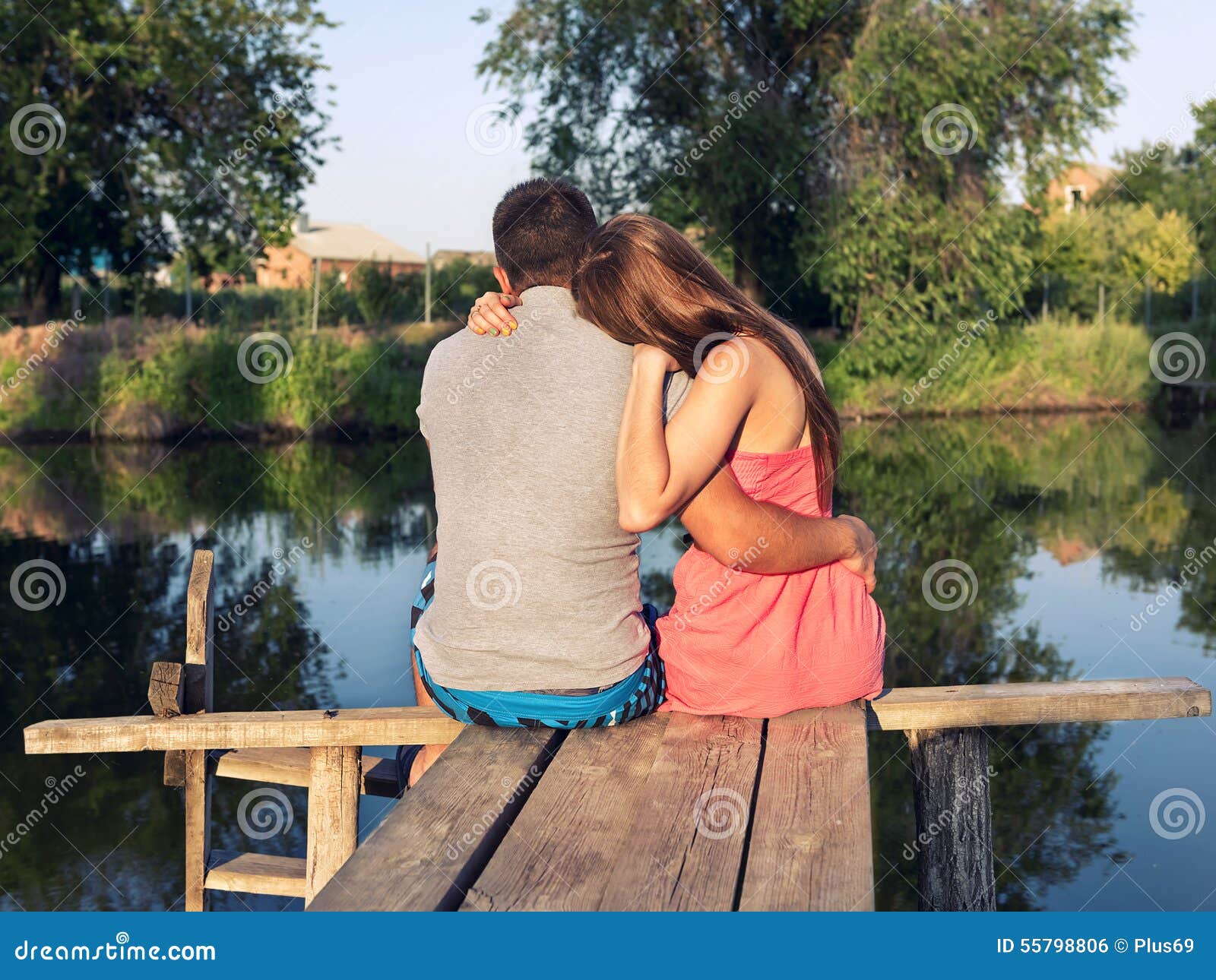 Young Couple Sitting Embracing on the Bridge by the River Stock Photo ...