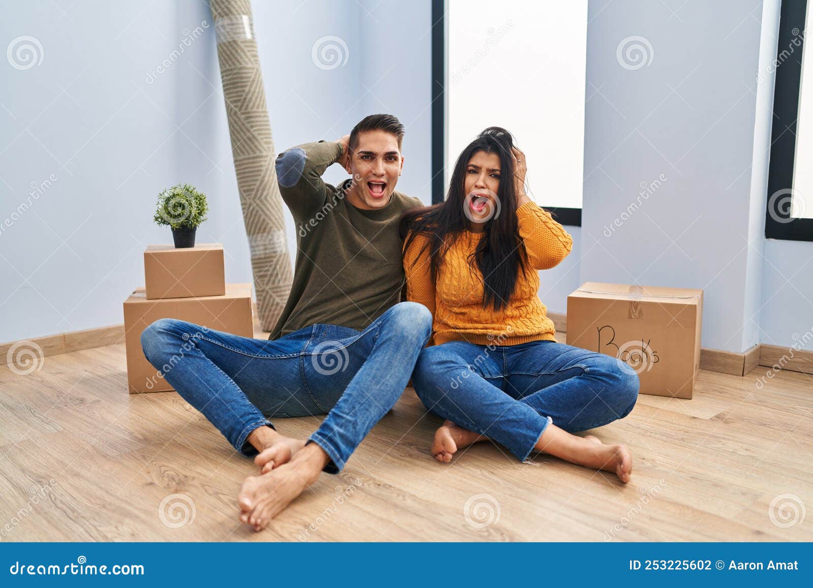 Young Couple Sitting On The Floor At New Home Crazy And Scared With