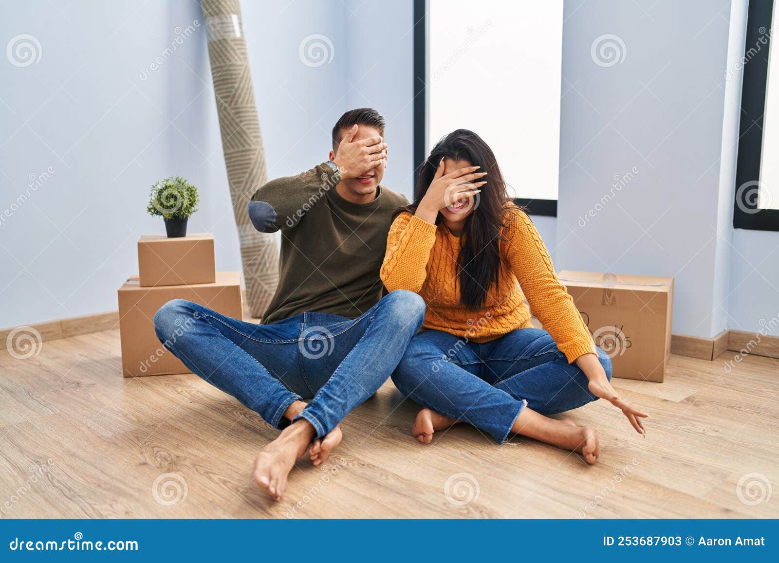 Young Couple Sitting On The Floor At New Home Smiling And Laughing With