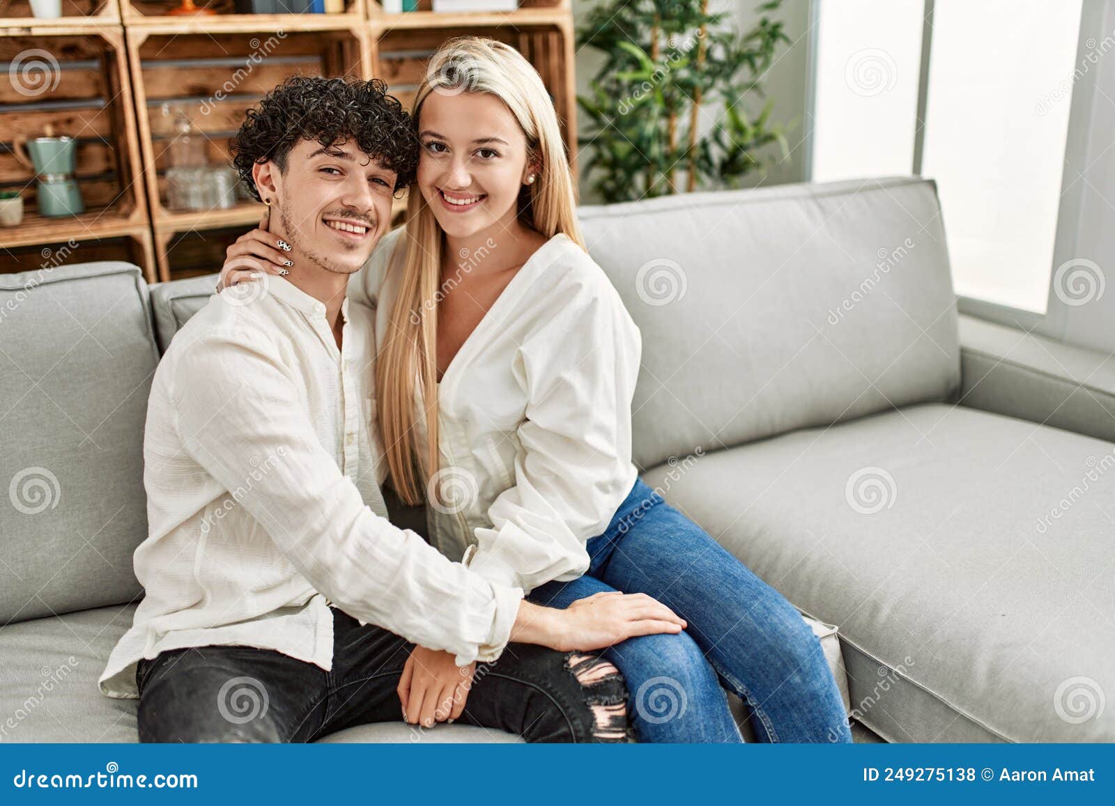 Young Couple Sitting on the Sofa Hugging at Home Stock Photo - Image of ...