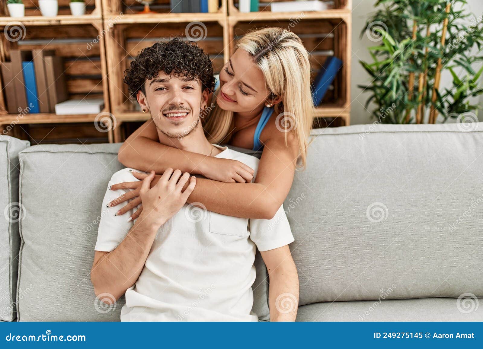 Young Couple Sitting on the Sofa Hugging at Home Stock Image - Image of ...