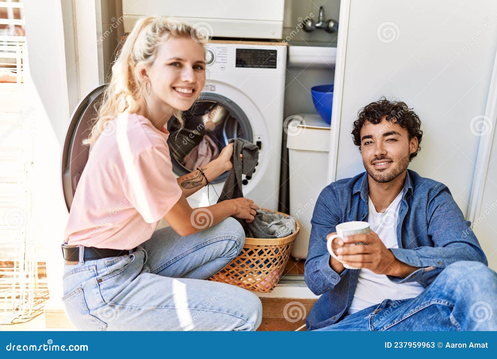 Young Couple Smiling Happy Drinking Coffee while Doing Laundry at Home ...