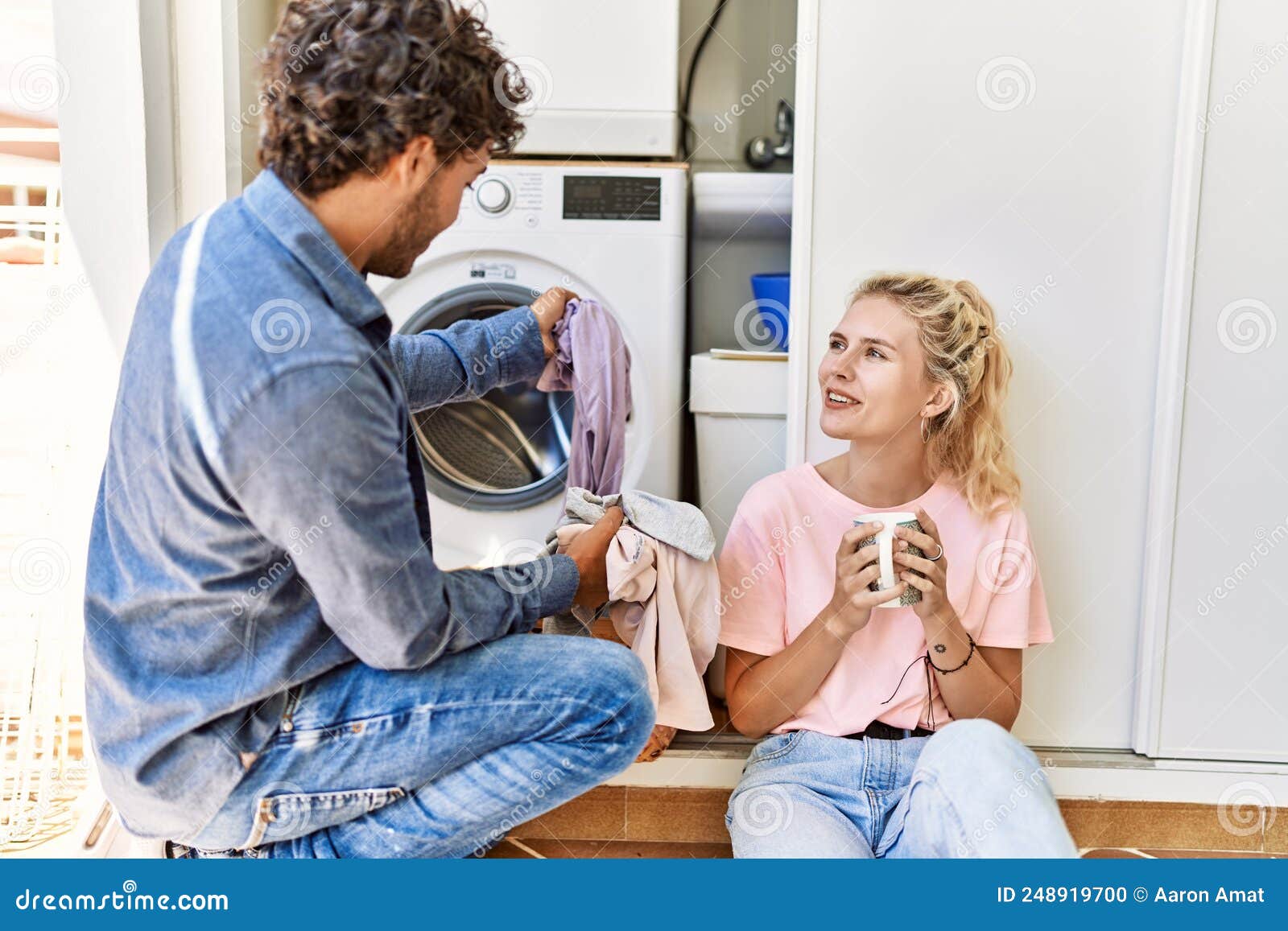 Young Couple Smiling Happy Drinking Coffee while Doing Laundry at Home ...