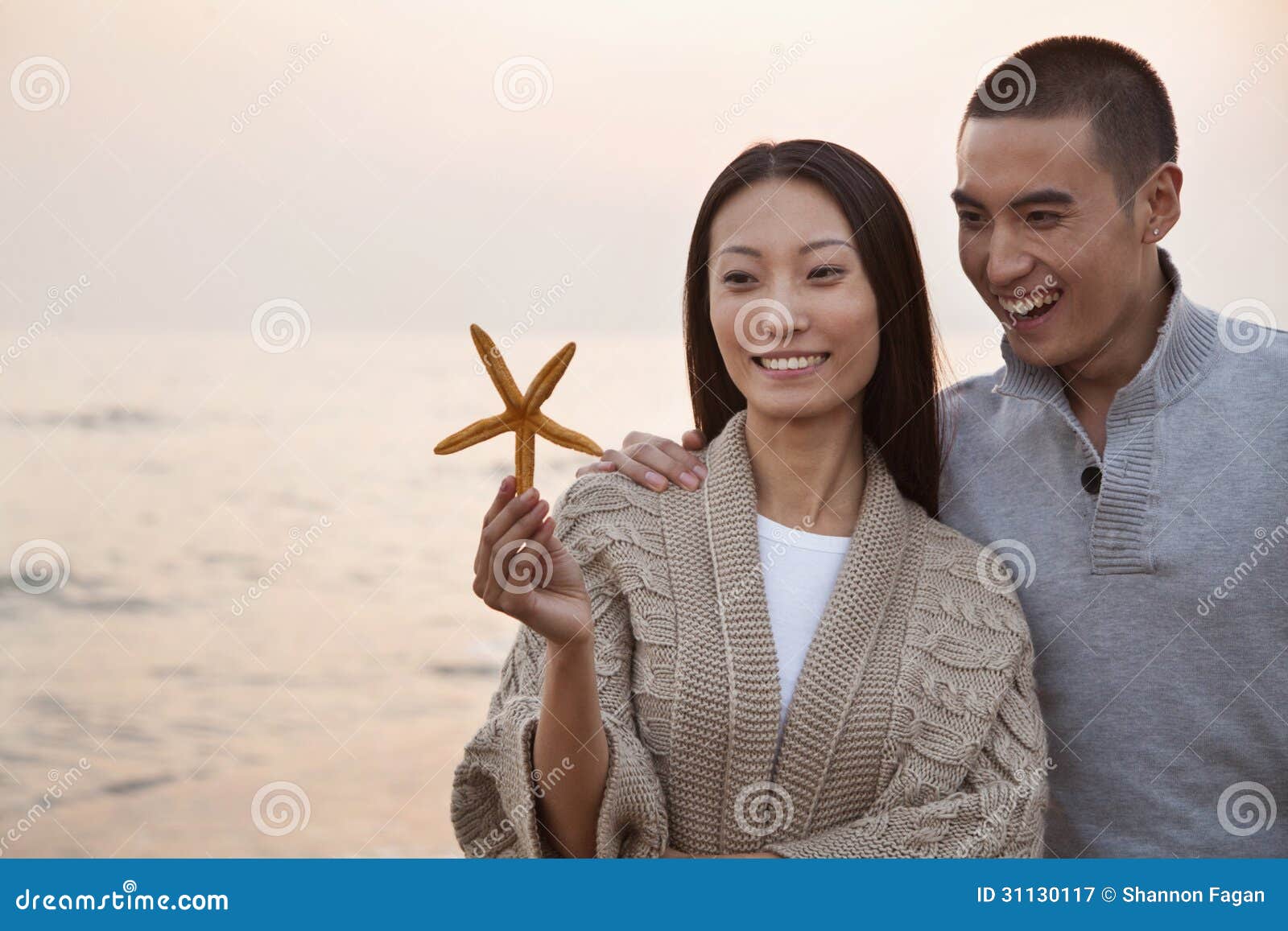 Young Couple Smiling and Looking at a Seashell Stock Image - Image of ...