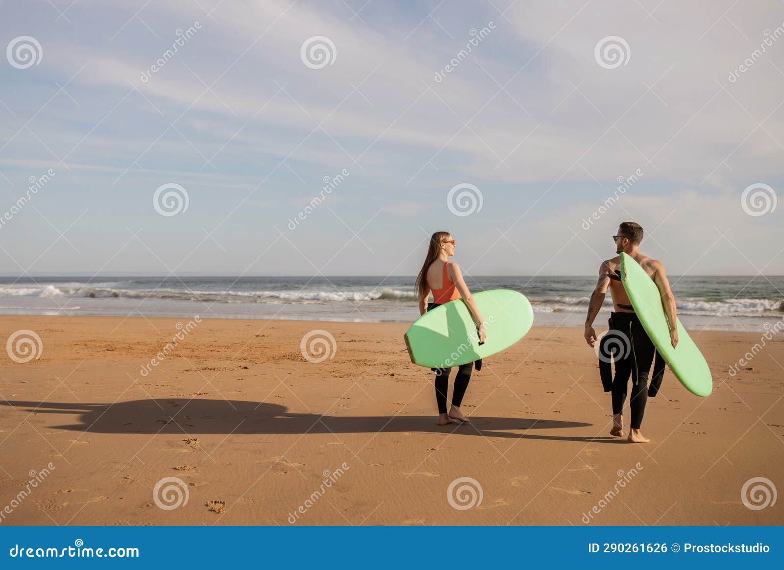 Young Couple Of Surfers Walking On The Seashore With Surfboards Stock