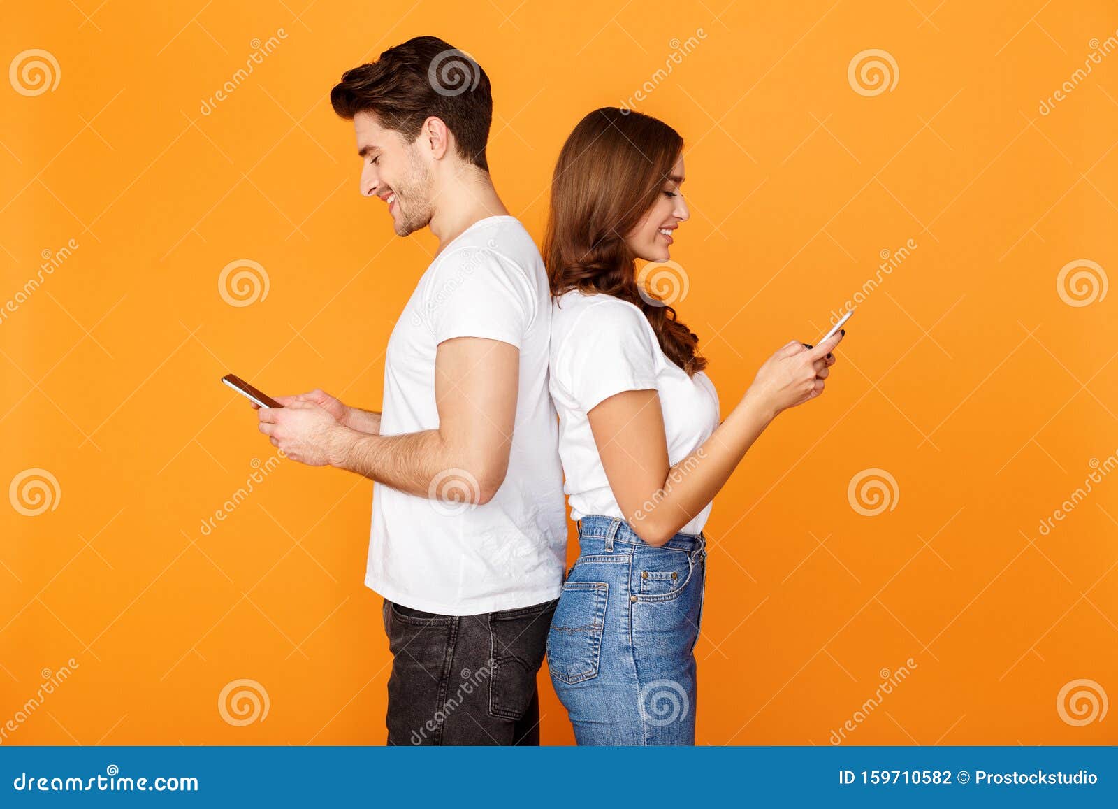 Young Couple Using Cellphones, Standing Back To Back Stock Photo ...
