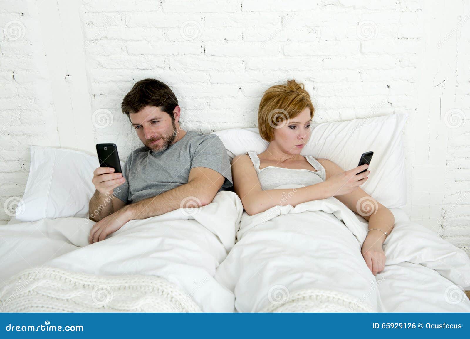 Young Couple Using Mobile Phone in Bed Ignoring Each Other in ...