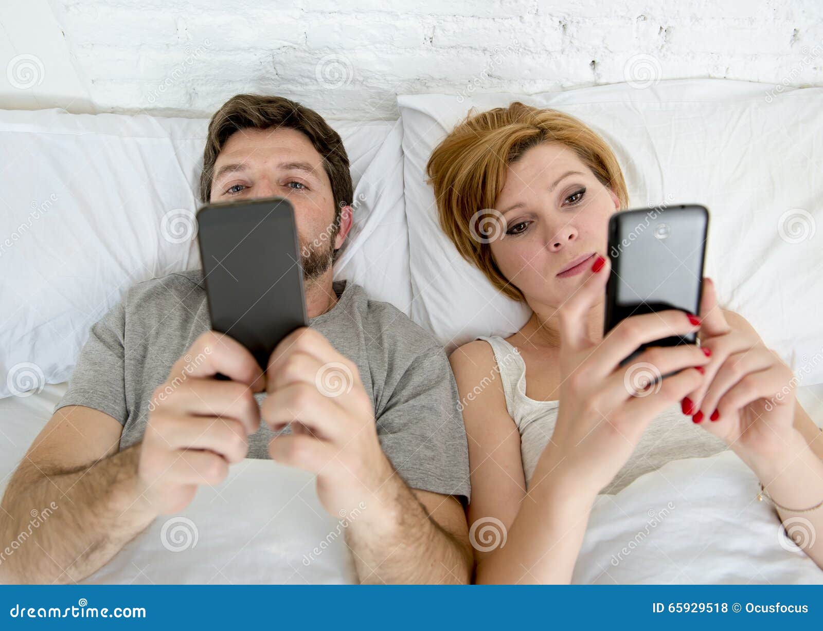 Young Couple Using Mobile Phone in Bed Ignoring Each Other in ...