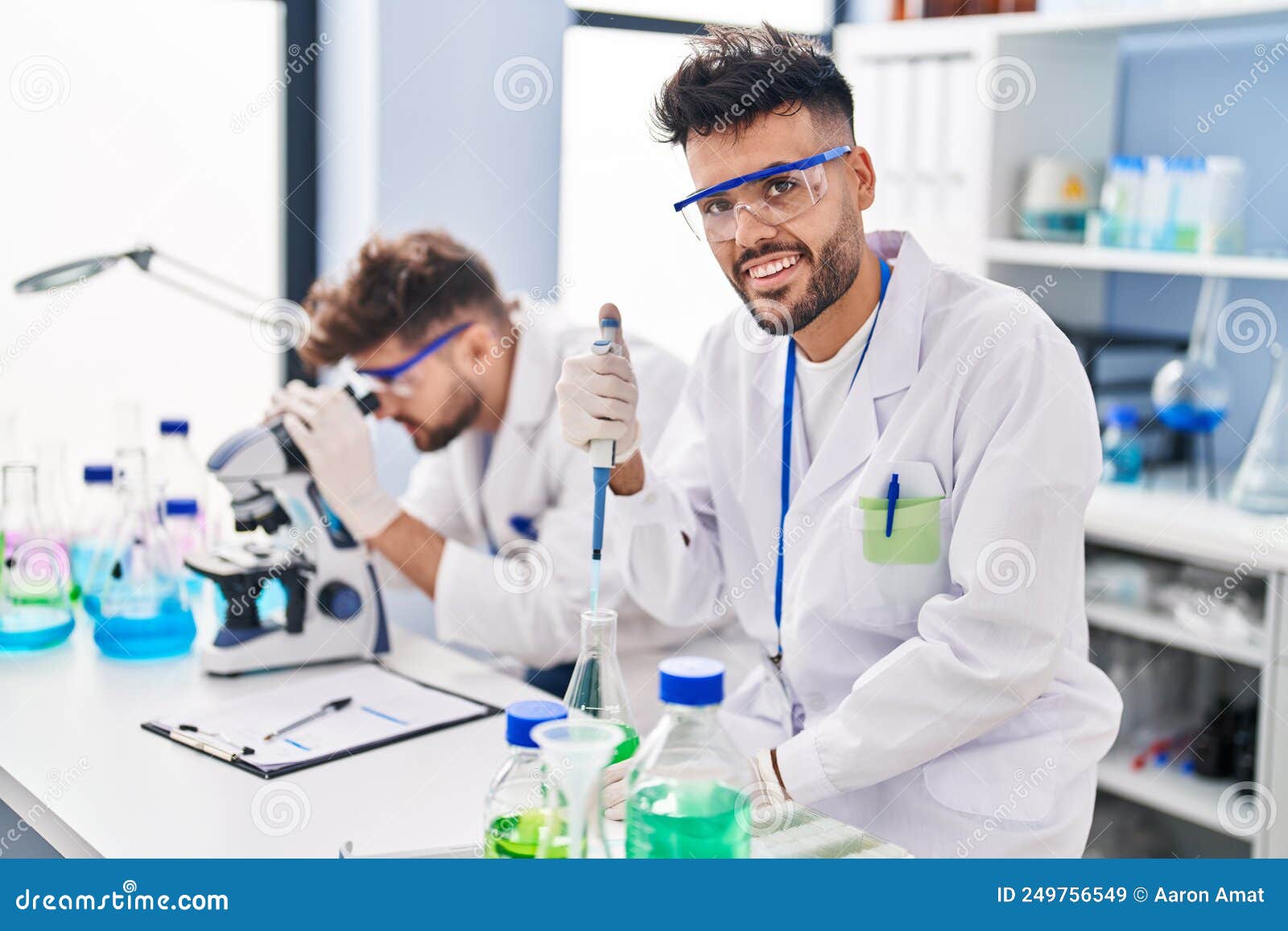 Young Couple Wearing Scientist Uniform Using Microscope and Pipette at ...
