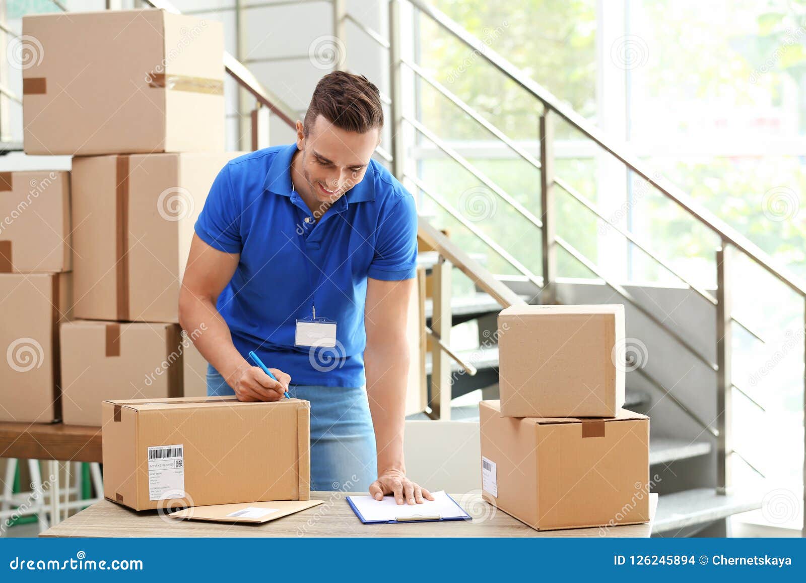 Courier Making Notes In Delivery Receipt Among Parcels At Table Stock ...