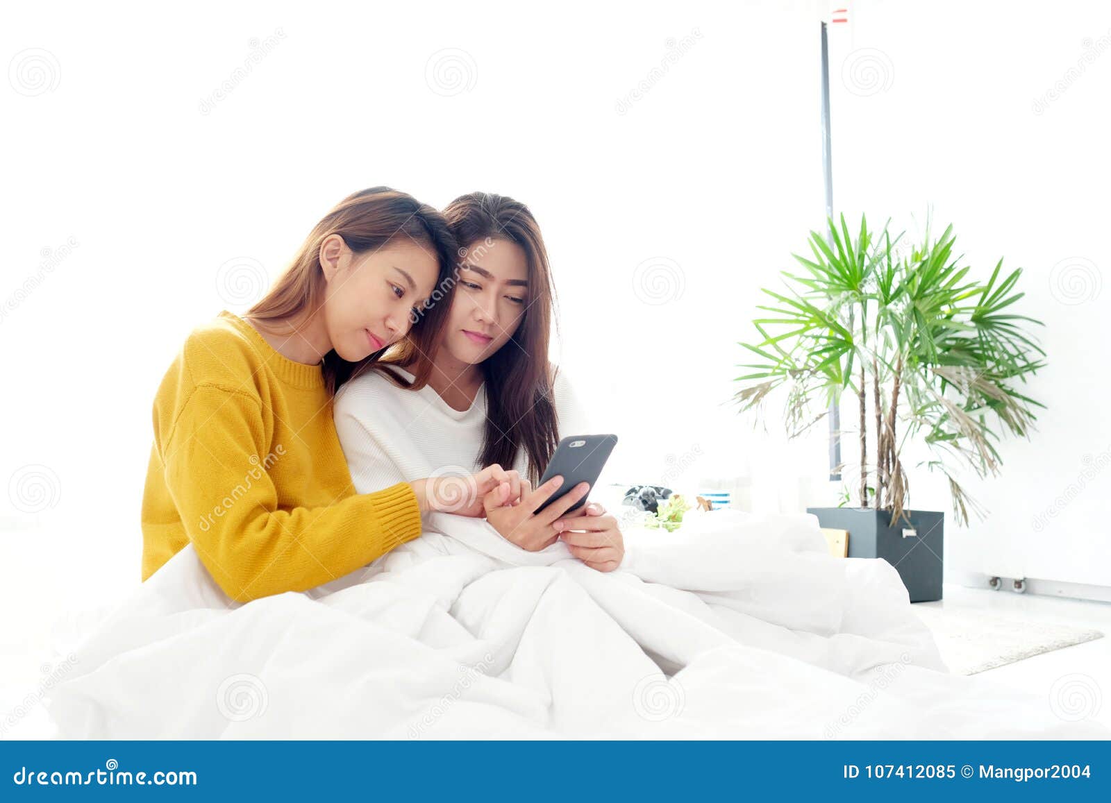 Young Cute Asia Lesbian Couple Using Smart Phone With Happiness Stock