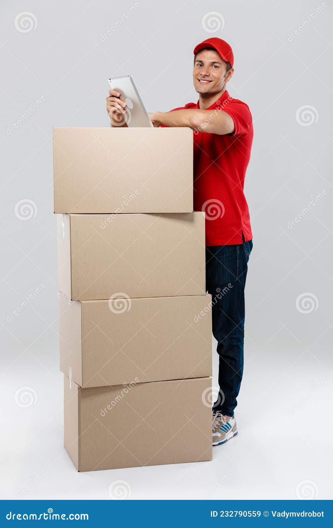 Young Delivery Man Using Tablet-computer while Posing with Boxes Stock ...