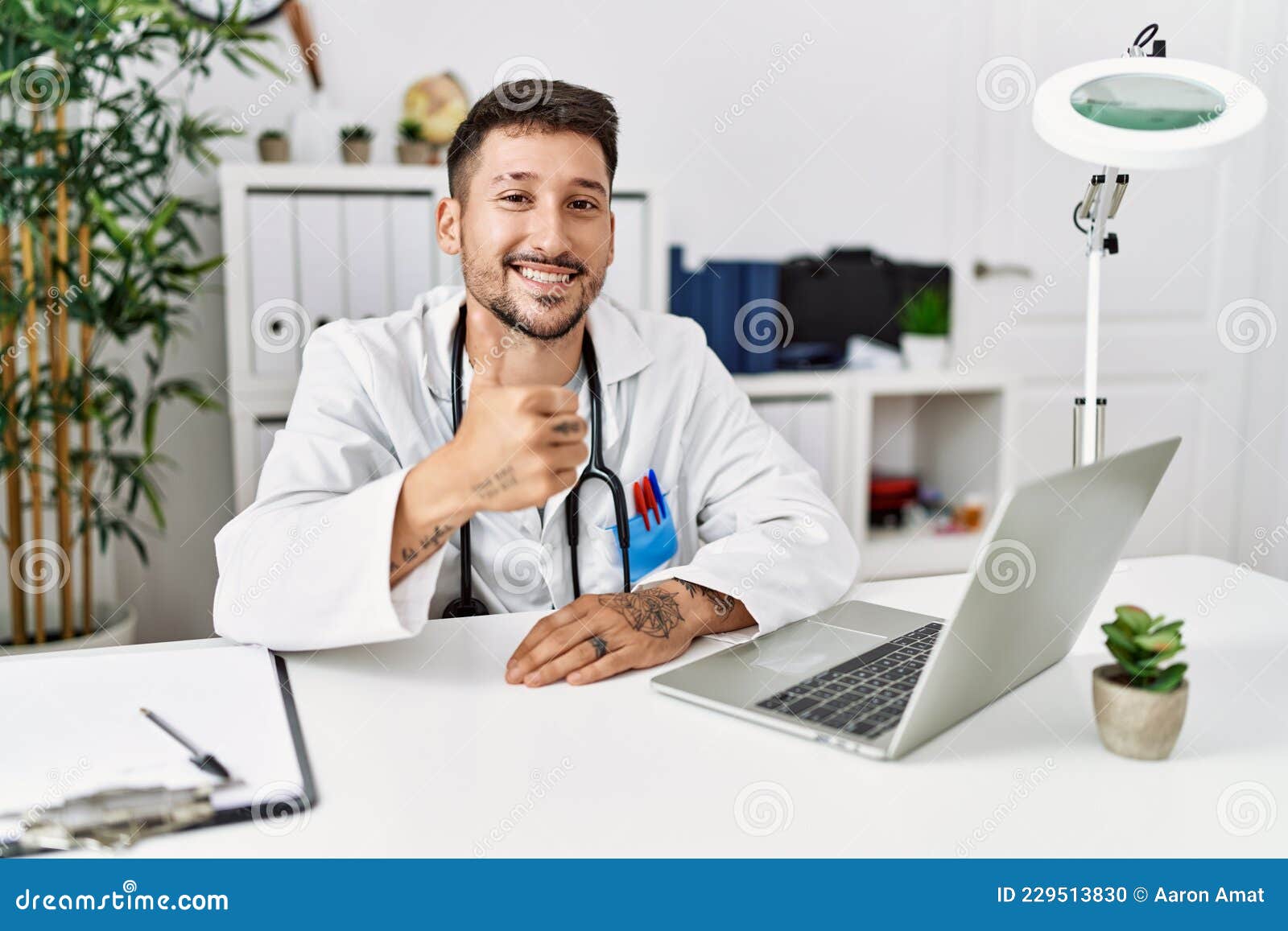 Young Doctor Working at the Clinic Using Computer Laptop Doing Happy ...