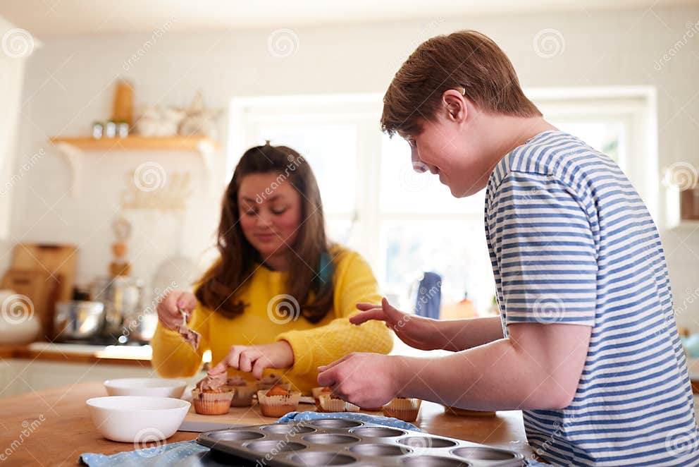Young Downs Syndrome Couple Decorating Homemade Cupcakes With Icing In