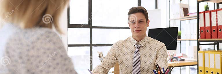 Young Economist Looks at Woman Sitting at Table by Clipboard Stock ... Young Economist Looks at Woman Sitting at Table by Clipboard Stock ...