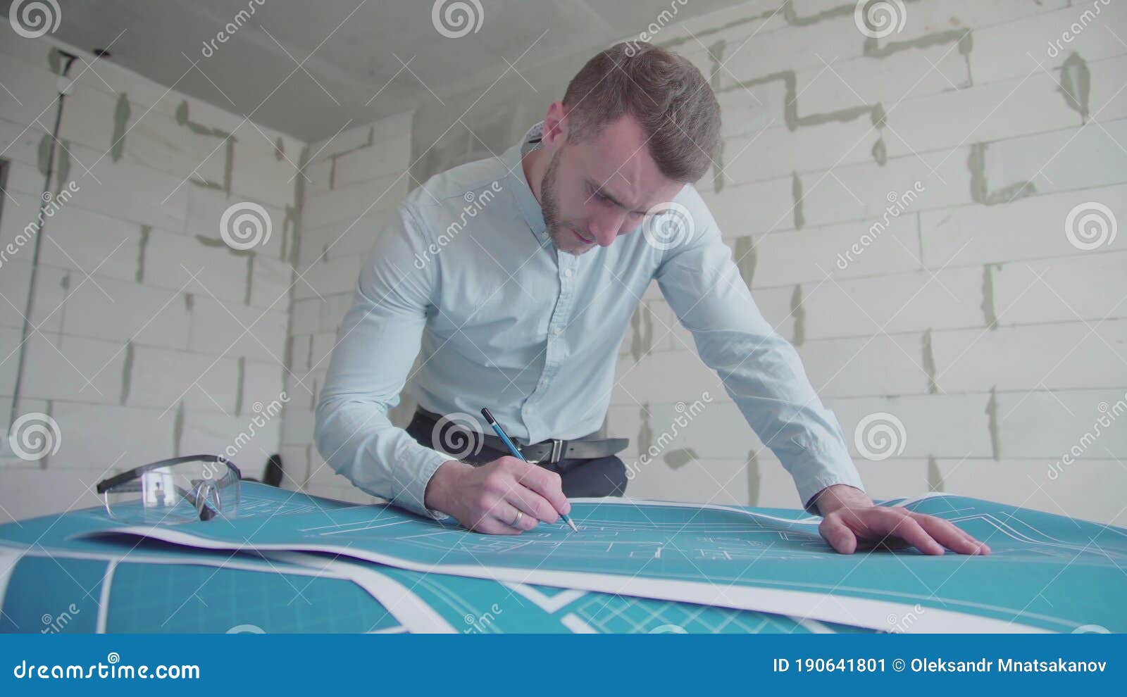 Young Engineer-architect in a Bright Room Works with Drawings Laid Out ...