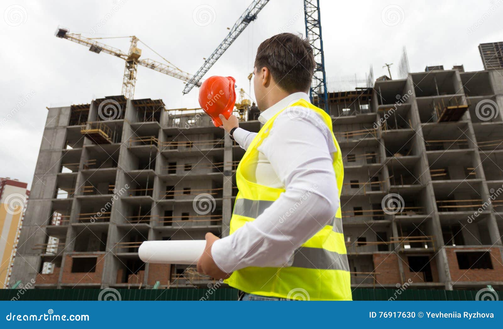 Young Engineer Holding Blueprints and Pointing at Building Site Stock ...