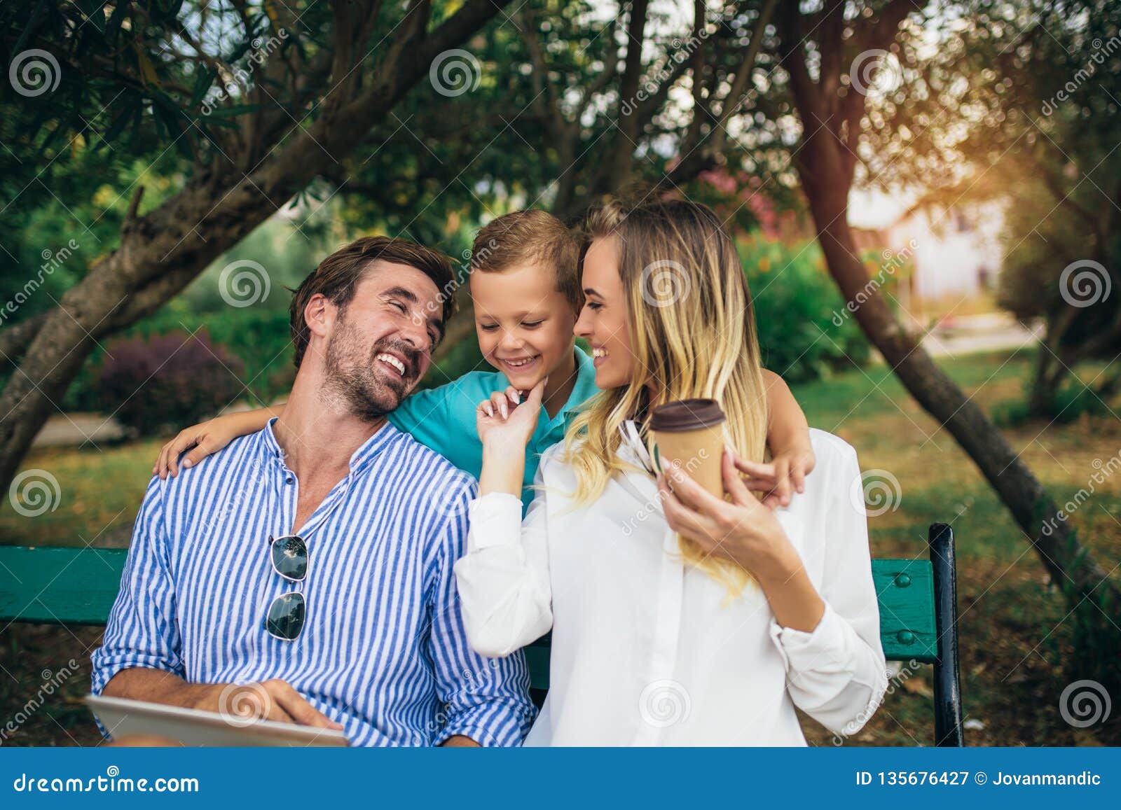 Family Talking and Looking at Digital Tablet in Park Stock Image ...