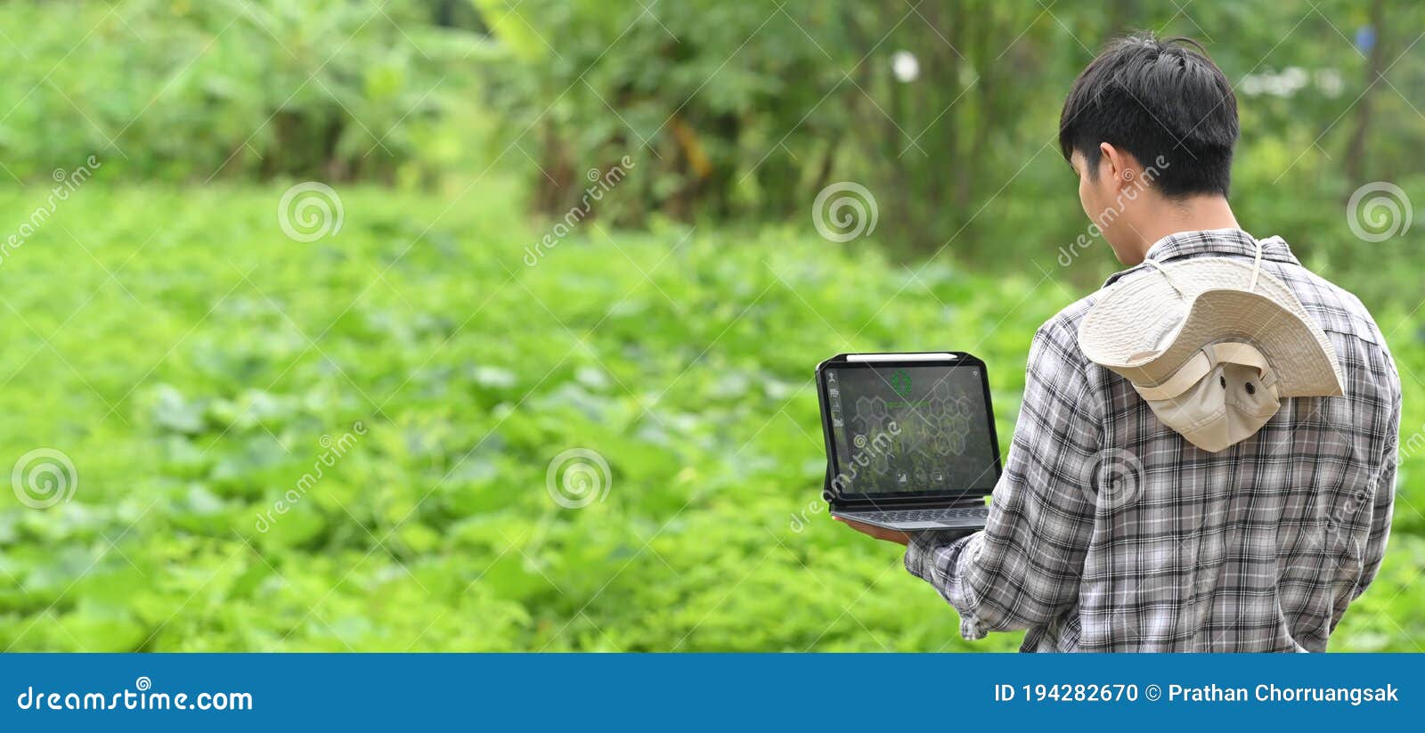 A Young Farmer is Using a Computer Laptop while Standing among the ...