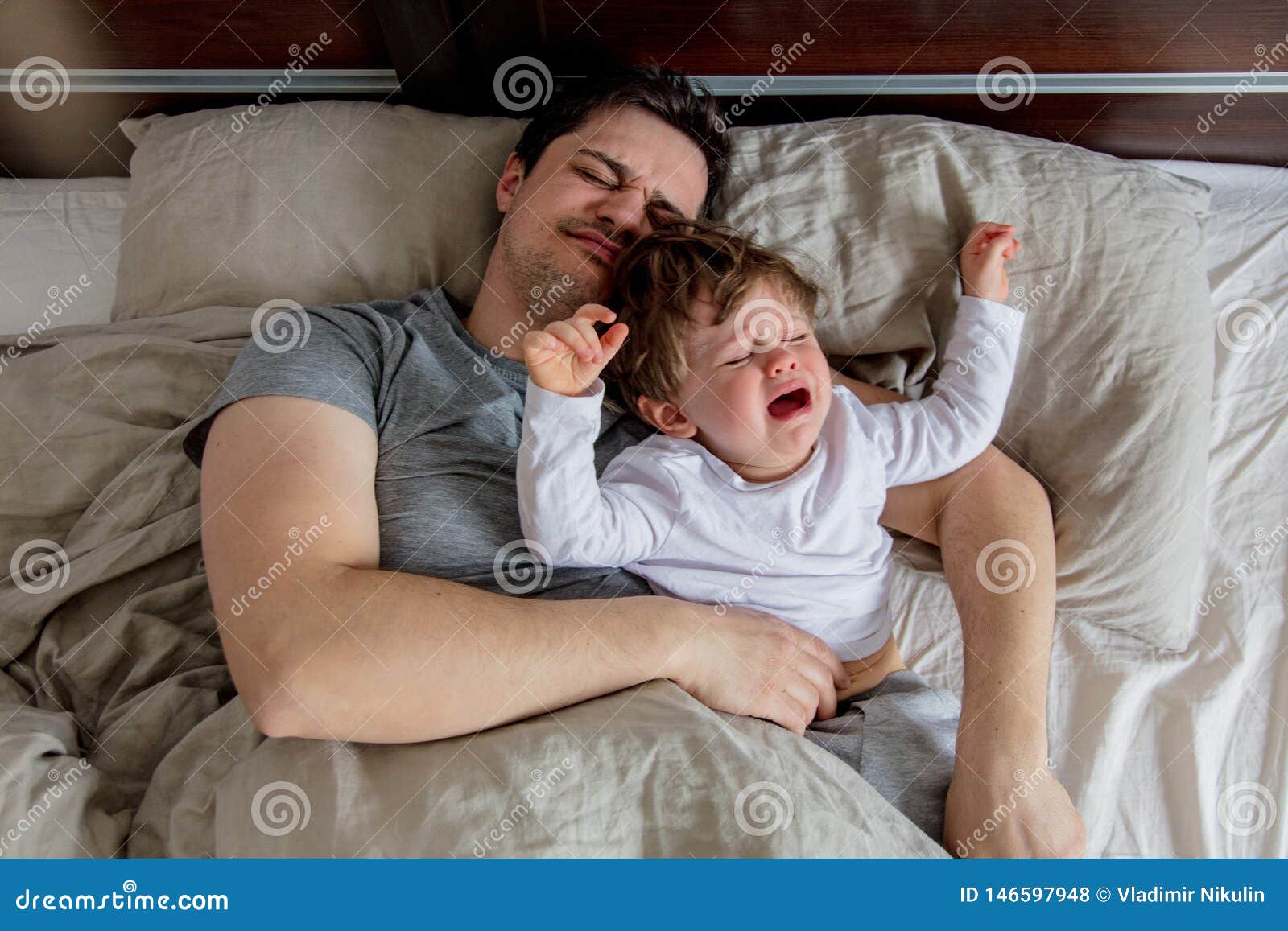 Young Father Lying Down in a Bed with Crying Child Stock Photo - Image ...