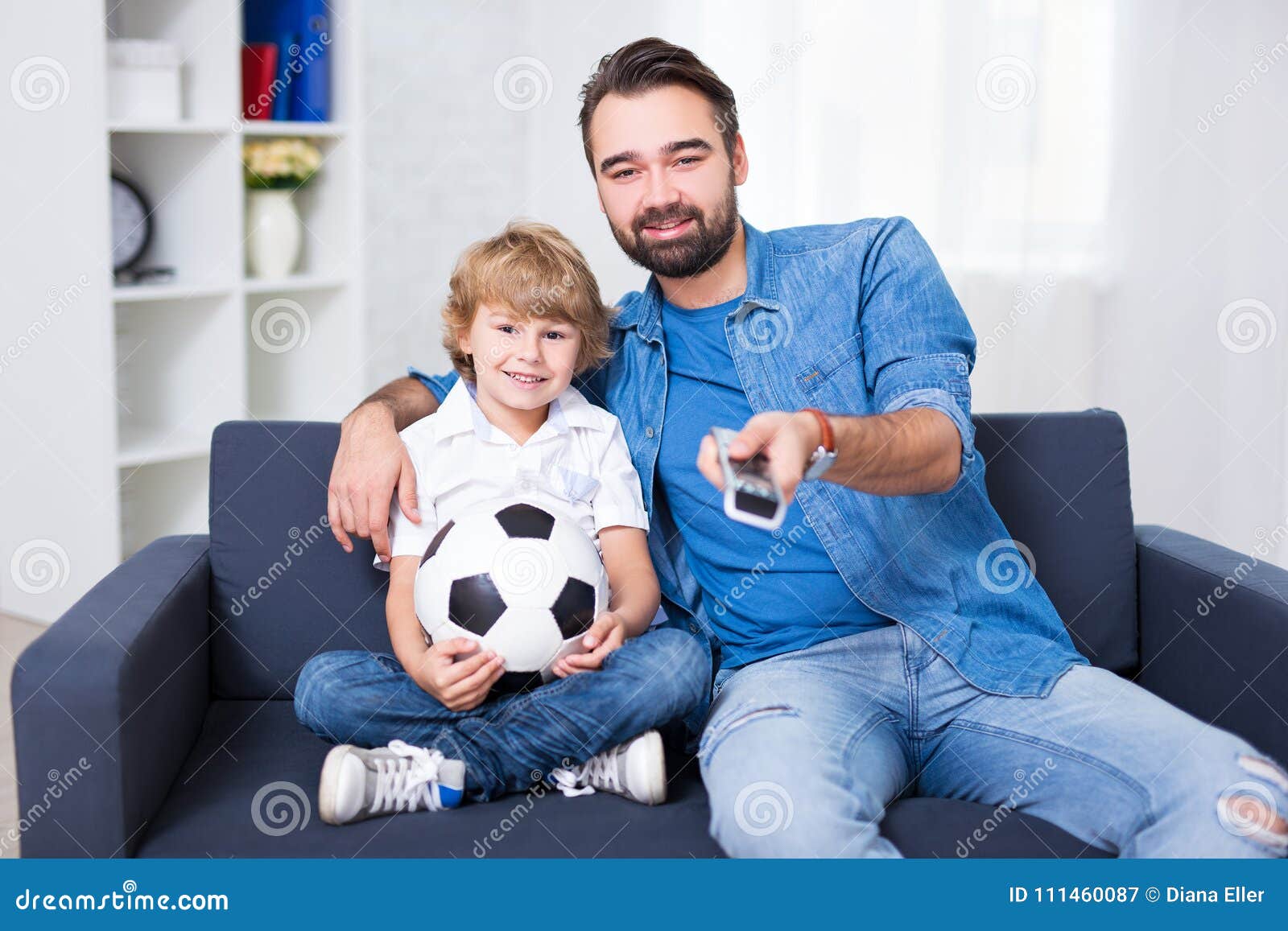 Young Father And Son Sitting On Sofa And Watching Football Stock Image