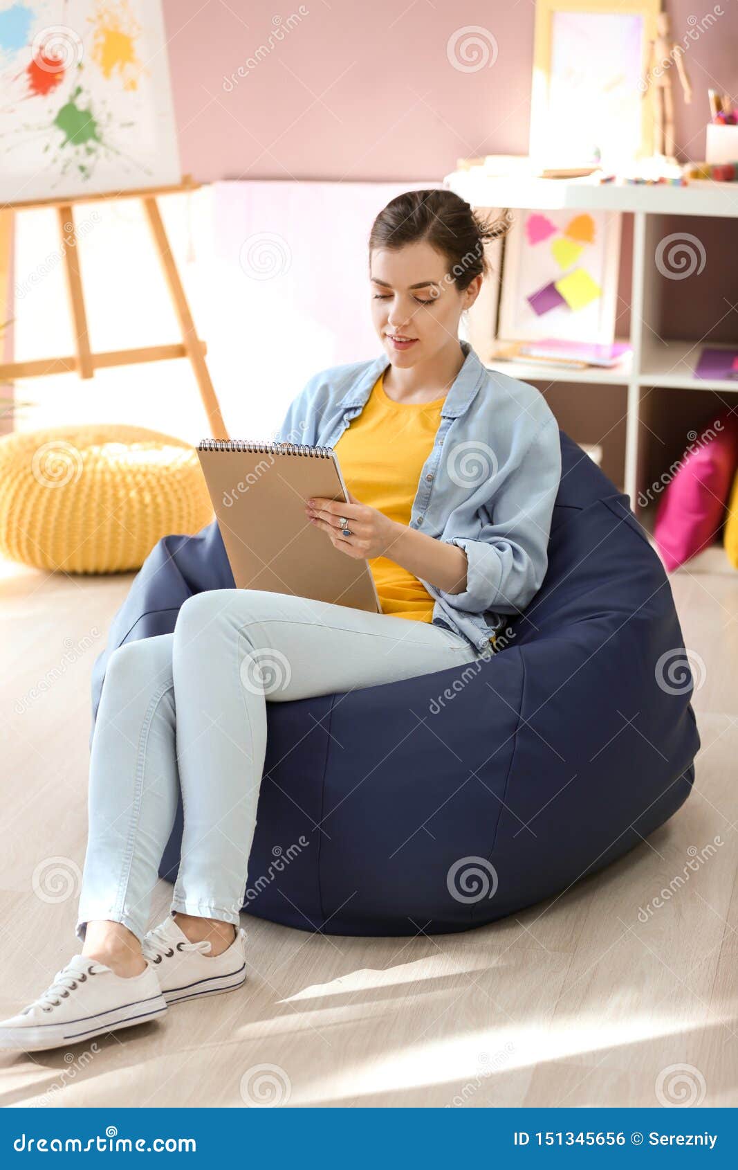Young Female Painter Sitting on Beanbag Chair in Studio Stock Photo ...
