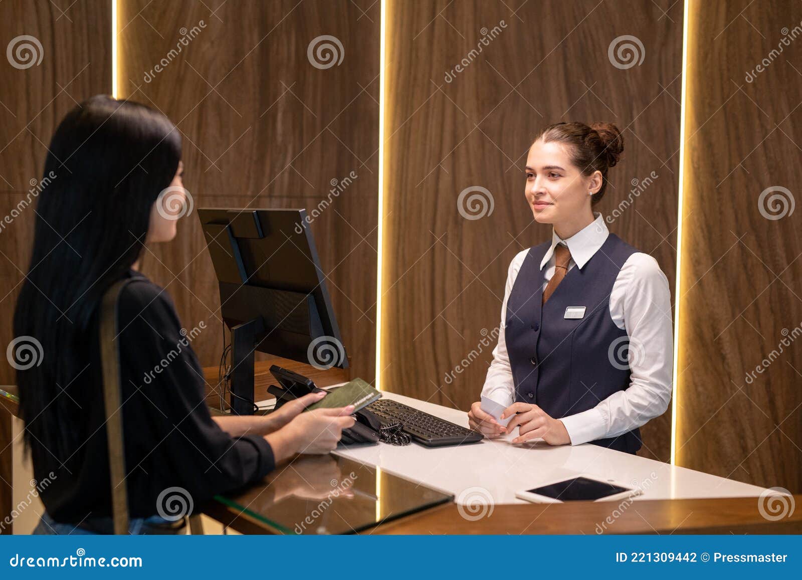 Young Female Receptionist Serving One of Clients Stock Photo - Image of ...