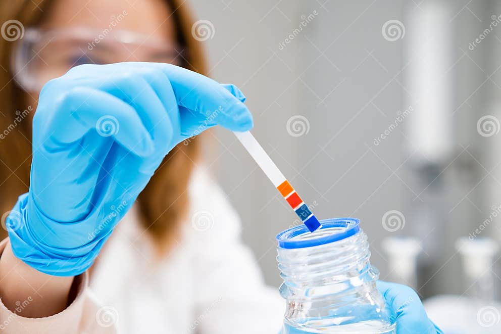 Young Female Scientist Measures PH of the Solution Using Indicator Paper. Scientist in the ...