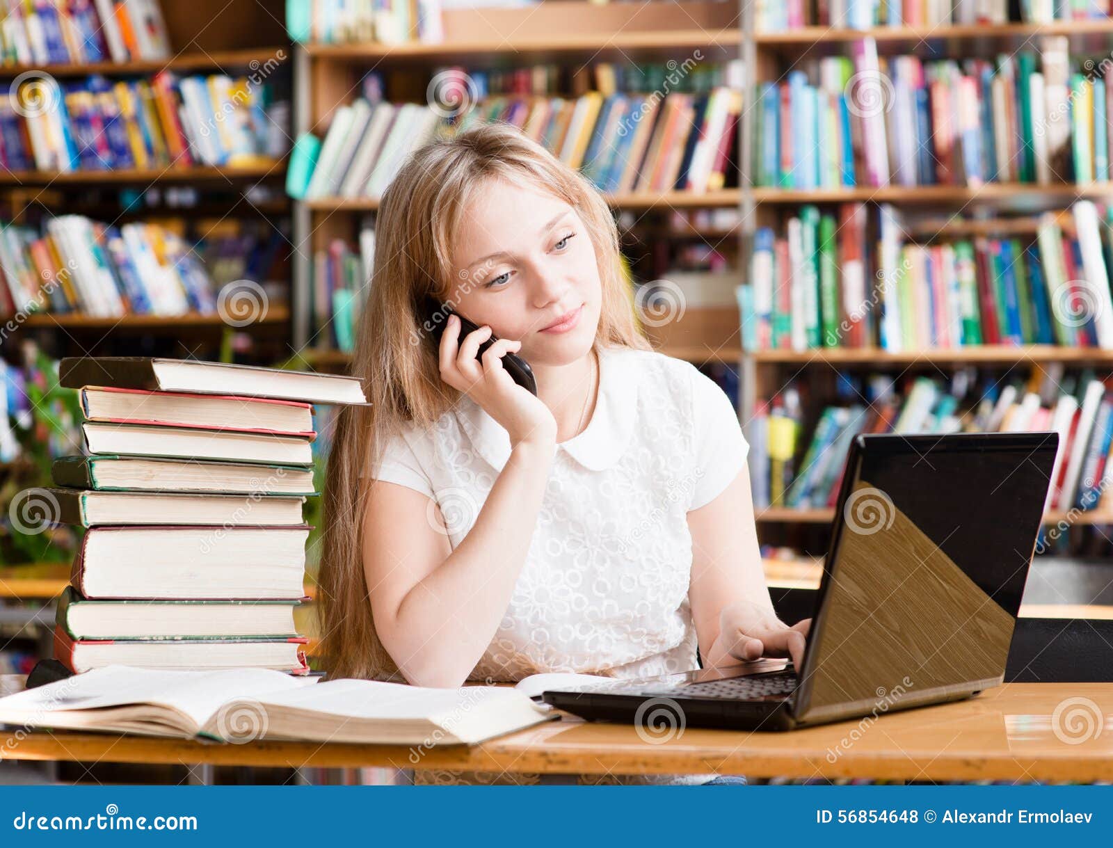 Young Female Student in Library Typing on Laptop and Talking on Stock ...