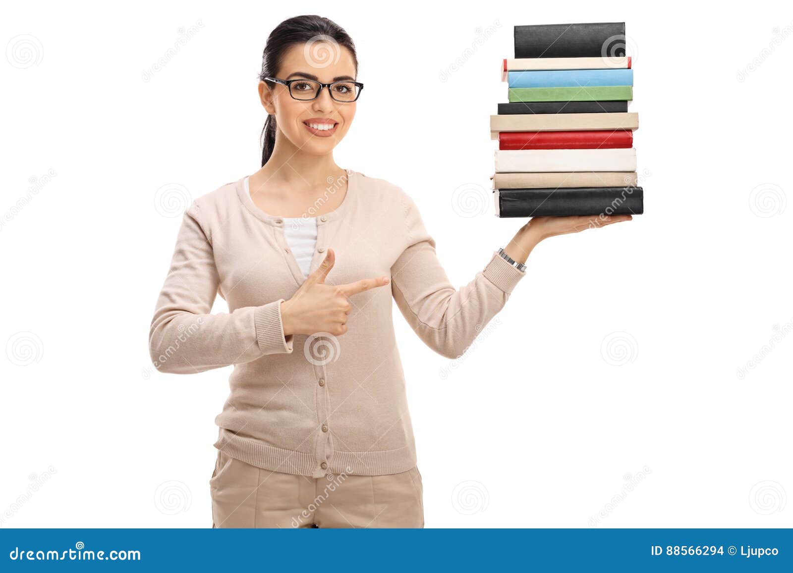 Young Female Teacher Holding a Stack of Books and Pointing Stock Photo ...