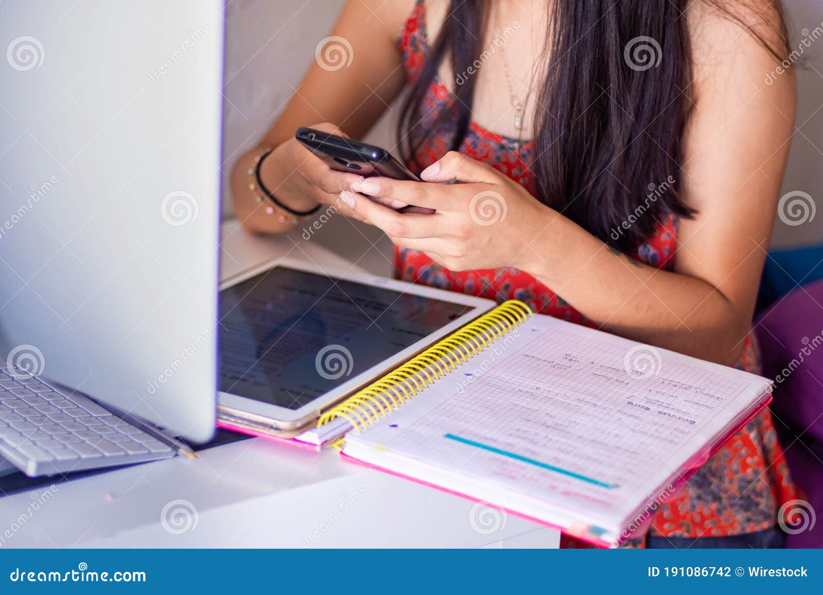 Young Female Using a Cellphone while Studying with a Tablet and ...