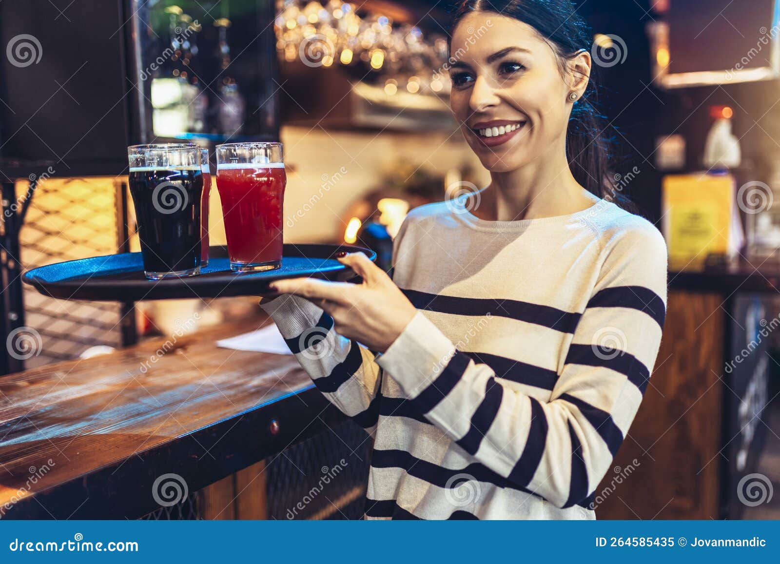 Female Waitress or Bartender Serving Drinks in a Bar Carrying a Tray ...