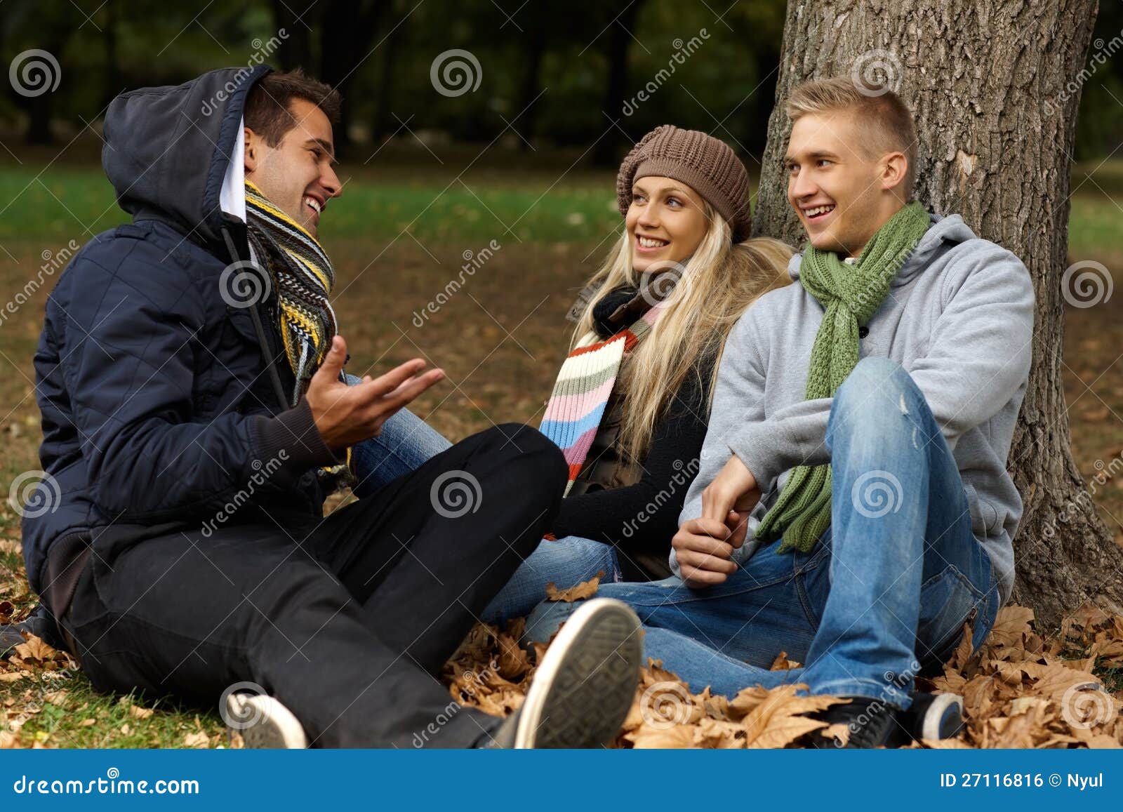 Young Friends Sitting on Ground in Autumn Park Stock Photo - Image of ...