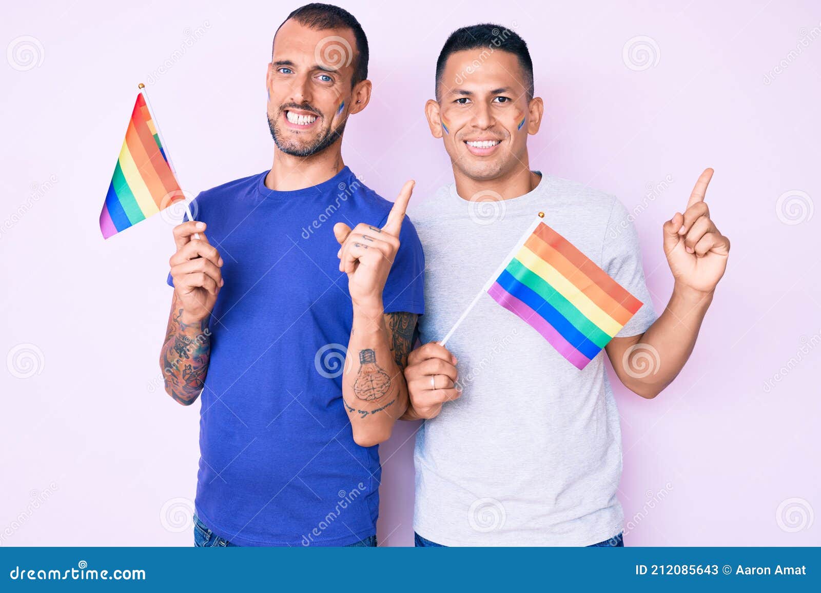 Young Gay Couple Of Two Men Holding Rainbow Lgbtq Flags Together