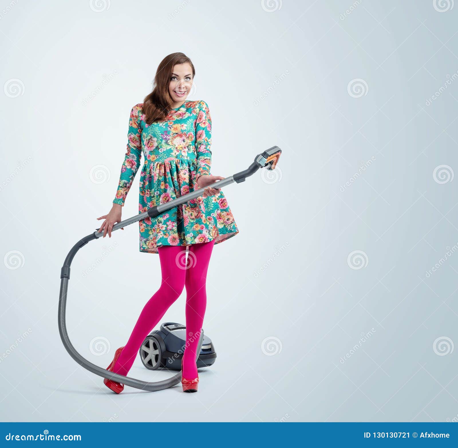 Young Girl In A Dress In Heels Posing With A Vacuum Cleaner On