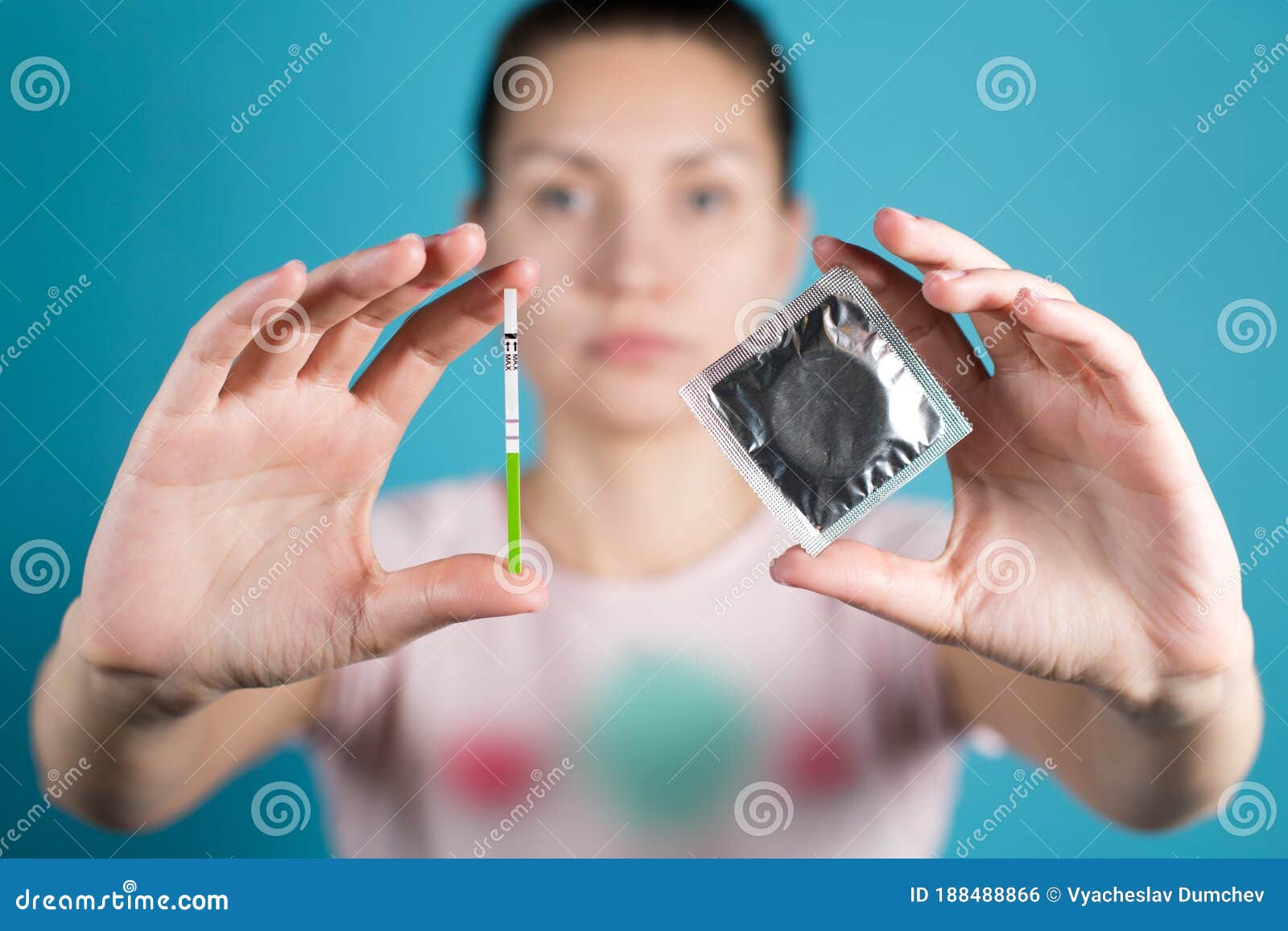 A Young Girl Holds Out A Condom And A Positive Pregnancy Test Stock